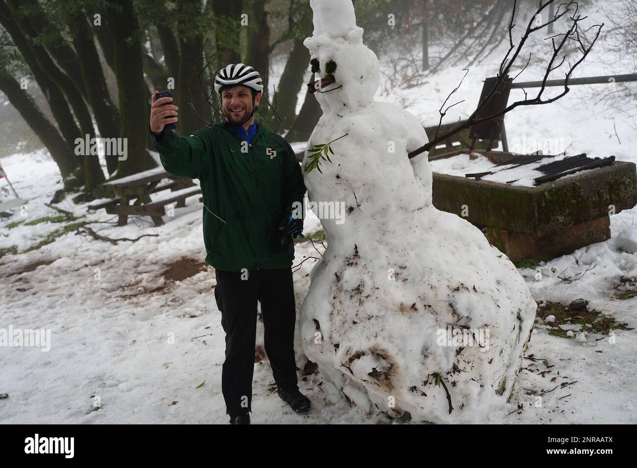 A man takes selfies with a snowman. Heavy snow and rain have pounded ...