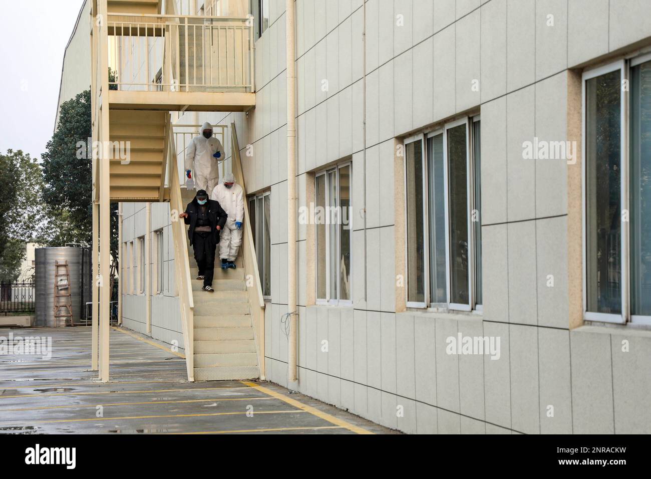 An old man is escorted out of a hotel accommodating isolated people ...