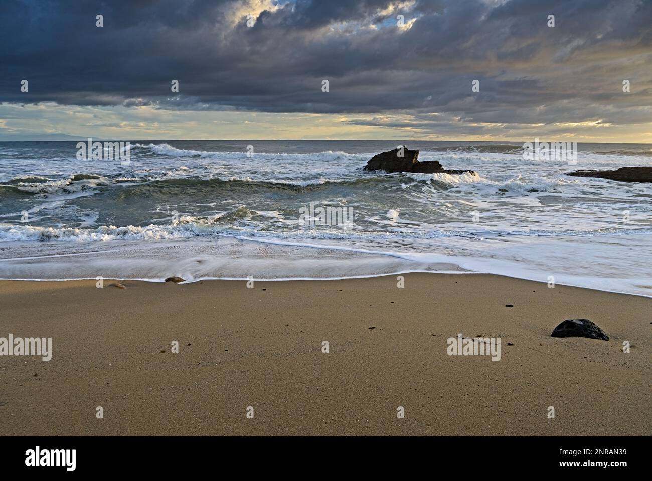 Sand beach with rocks and cloudy sky Stock Photo - Alamy