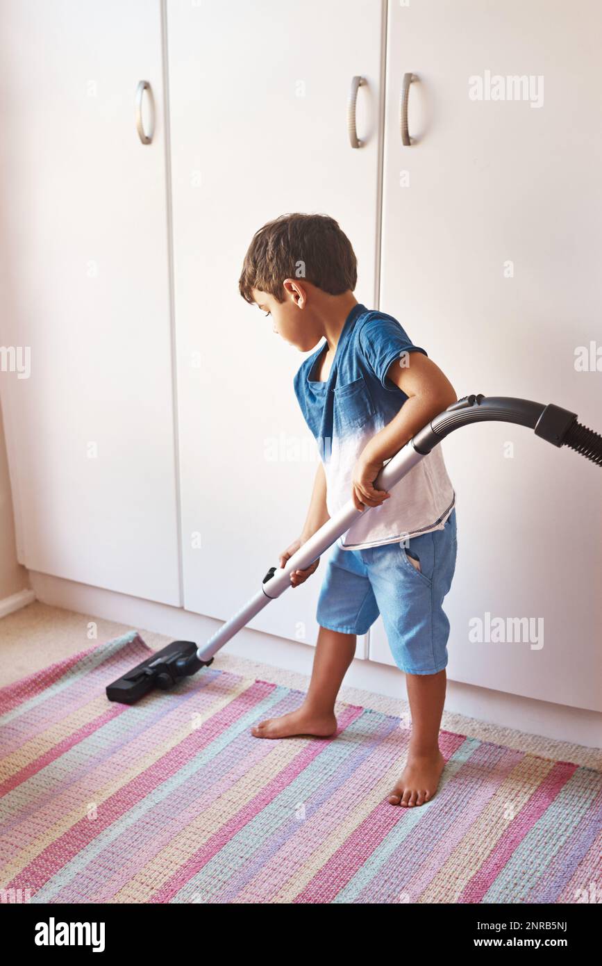 This isnt fun but it has to get done. a focused young little boy using ...