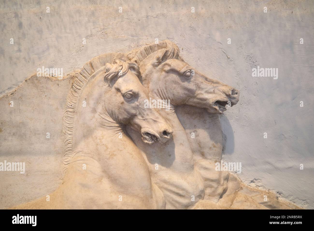 A small, white marble frieze of a a couple of horse heads in the wall ...