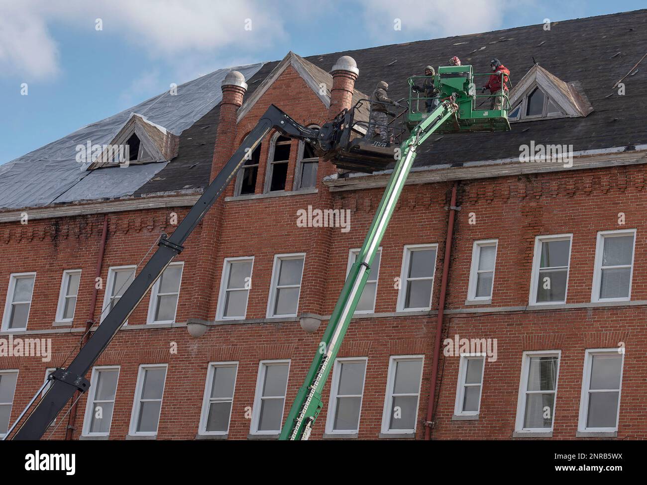 Workers bundled up against the cold work on the roof and windows of the ...