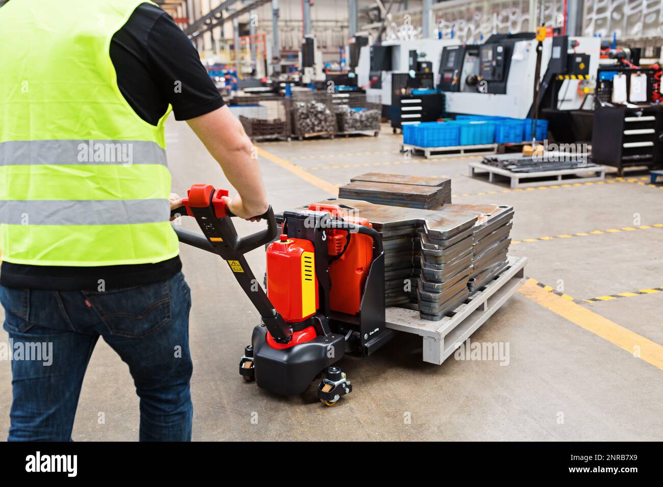 Warehouse worker dragging hand pallet truck or manual forklift with the ...