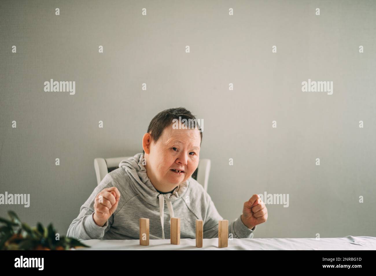 An elderly woman with down syndrome builds towers of their wooden toy ...