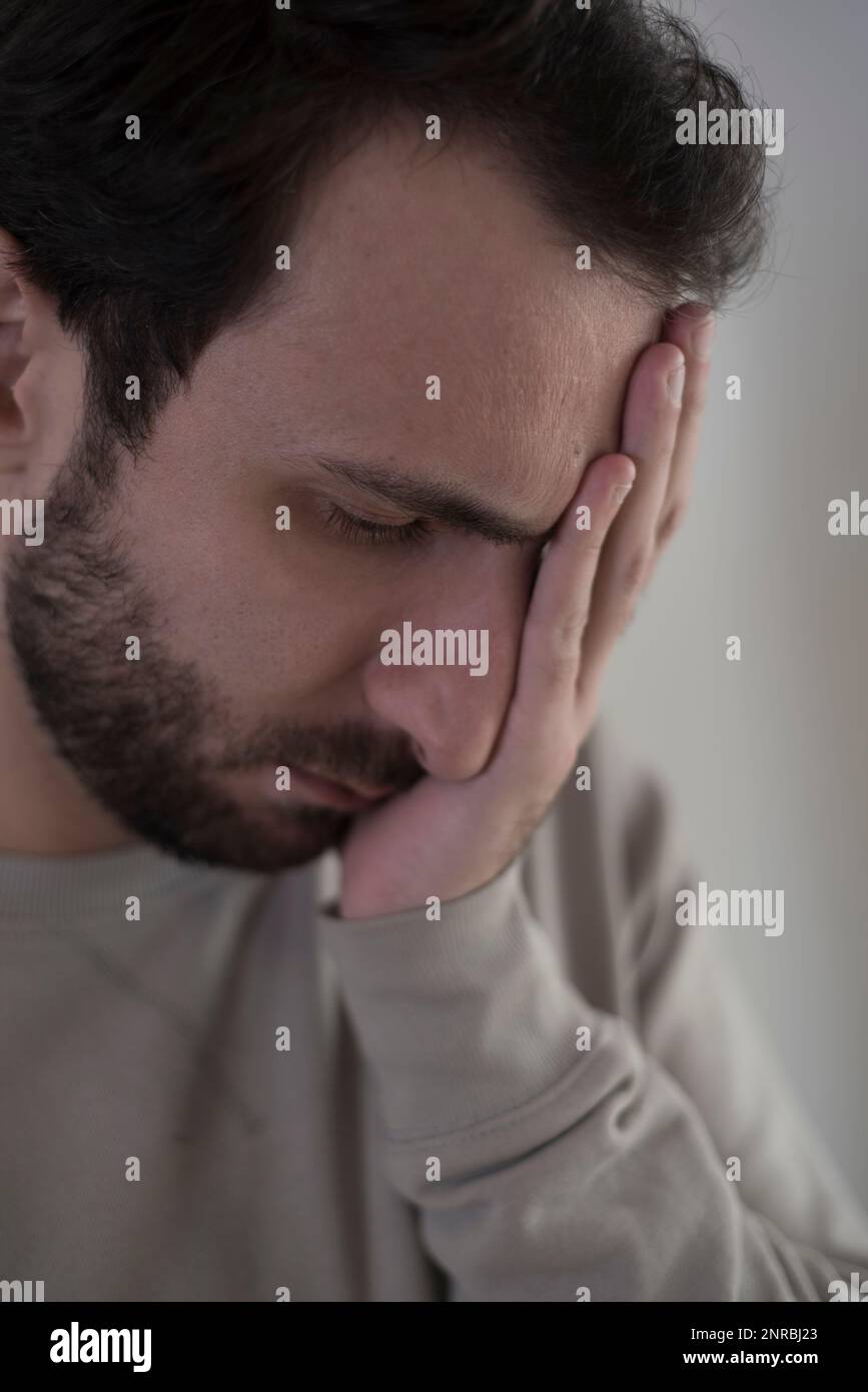 Stressed man hand on face looking down Stock Photo - Alamy