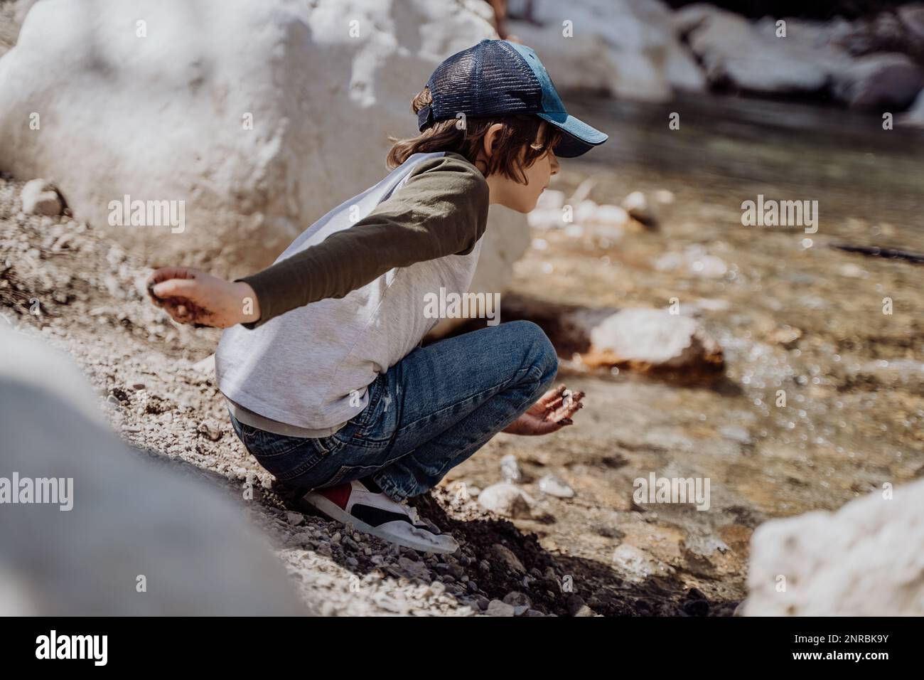Caucasian school boy throwing rocks into the canyon river. Kid child ...