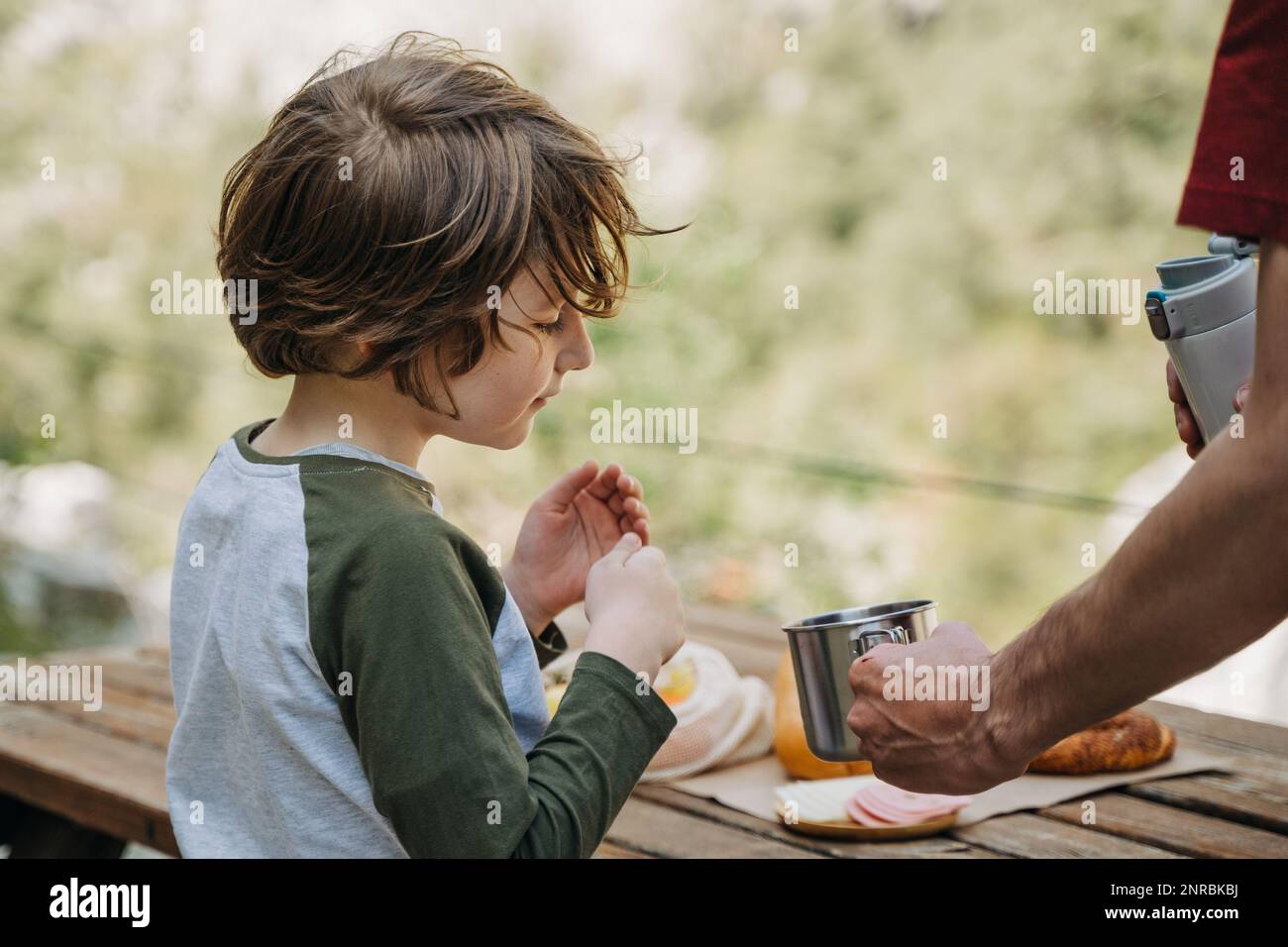 Father dad pours hot coffee tea from thermos into the mug on a family ...