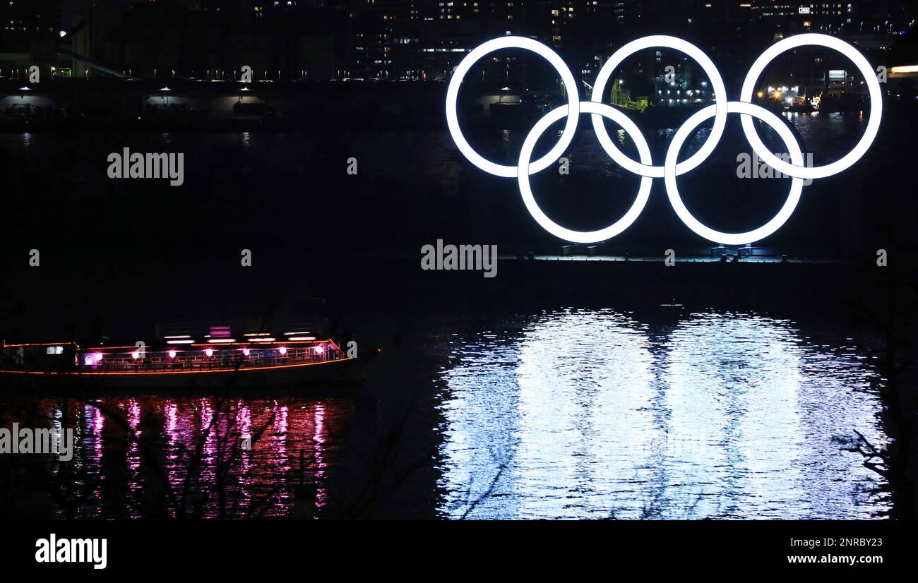 A monument of five-ring emblem is lit up on the water to enhance ...