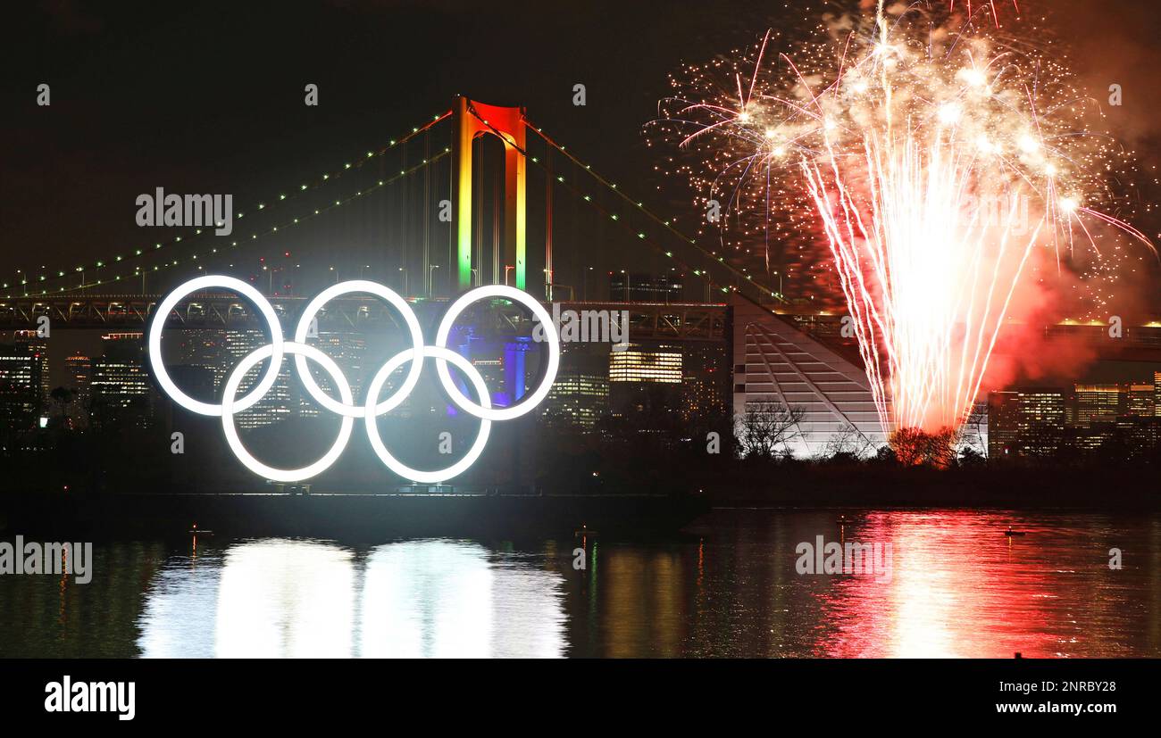 A monument of five-ring emblem is lit up on the water with fireworks to ...
