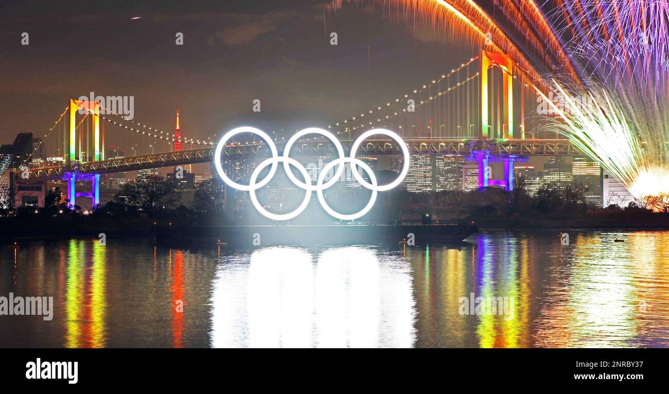 A monument of five-ring emblem is lit up on the water with fireworks to ...