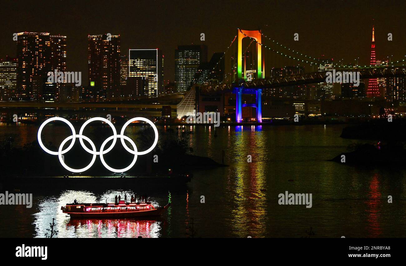 A monument of five-ring emblem is lit up on the water with fireworks to ...