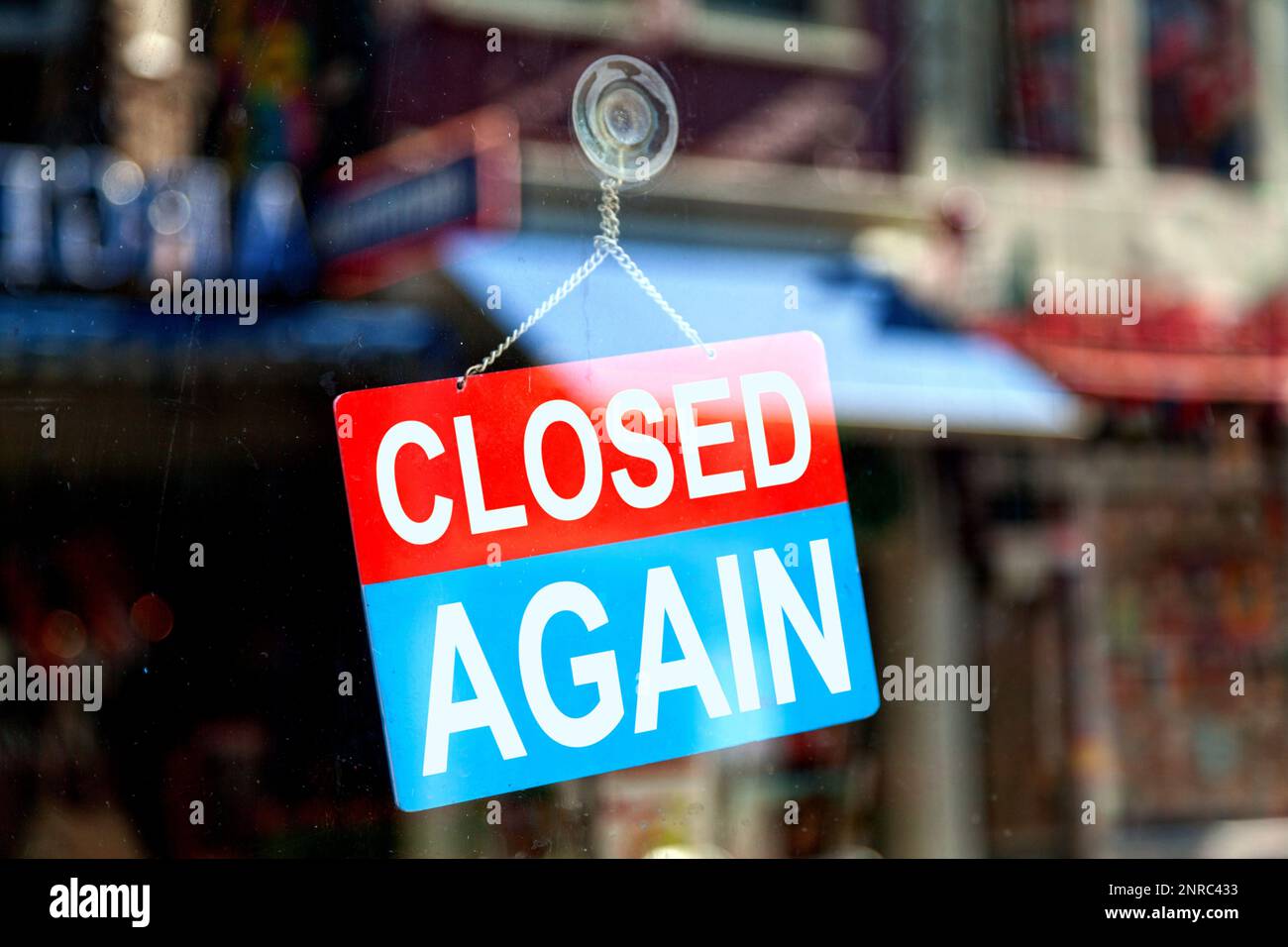 Red and blue sign in the window of a shop saying "Closed again Stock ...