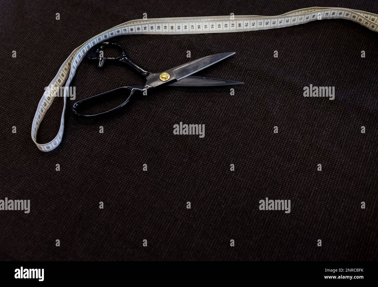 Scissors and measuring tape on fabric, top view. Tailoring equipment ...
