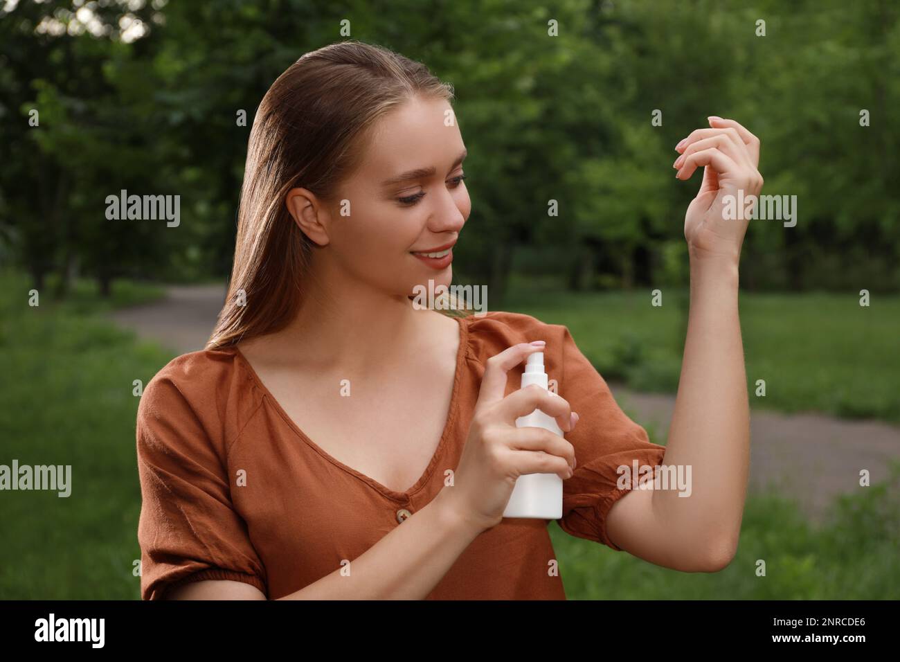 Woman applying insect repellent onto arm in park. Tick bites prevention ...