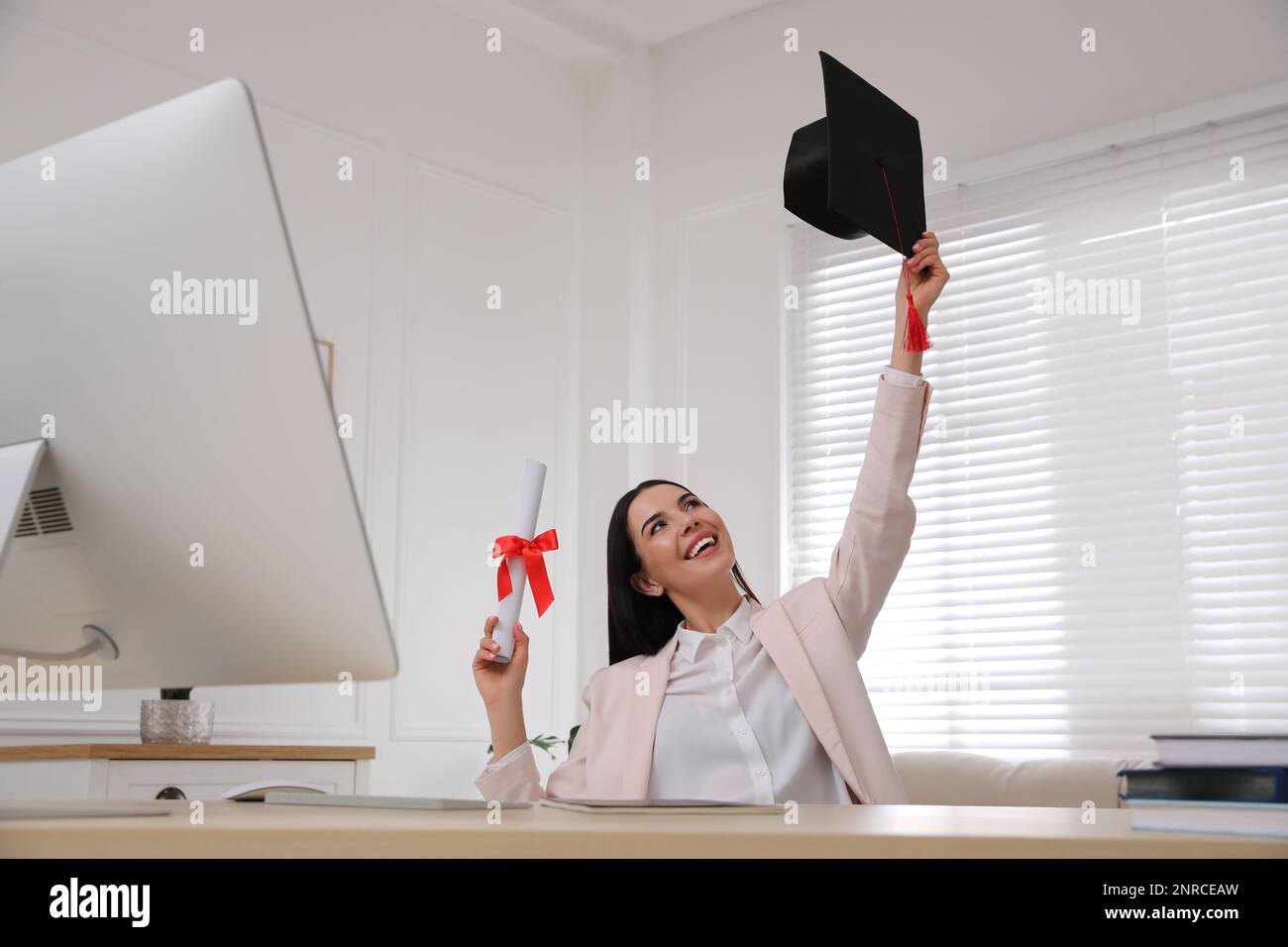 Happy student with graduation hat and diploma at workplace in office ...