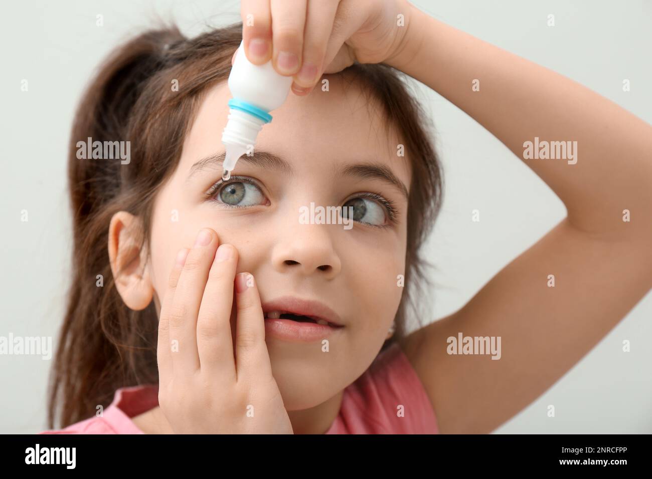 Adorable little girl using eye drops on white background, closeup Stock ...