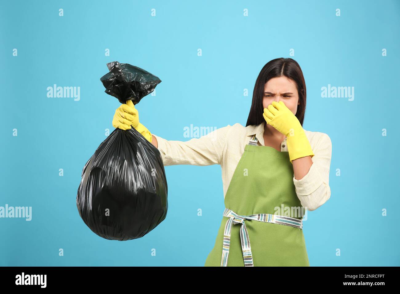 Woman holding full garbage bag on light blue background Stock Photo - Alamy