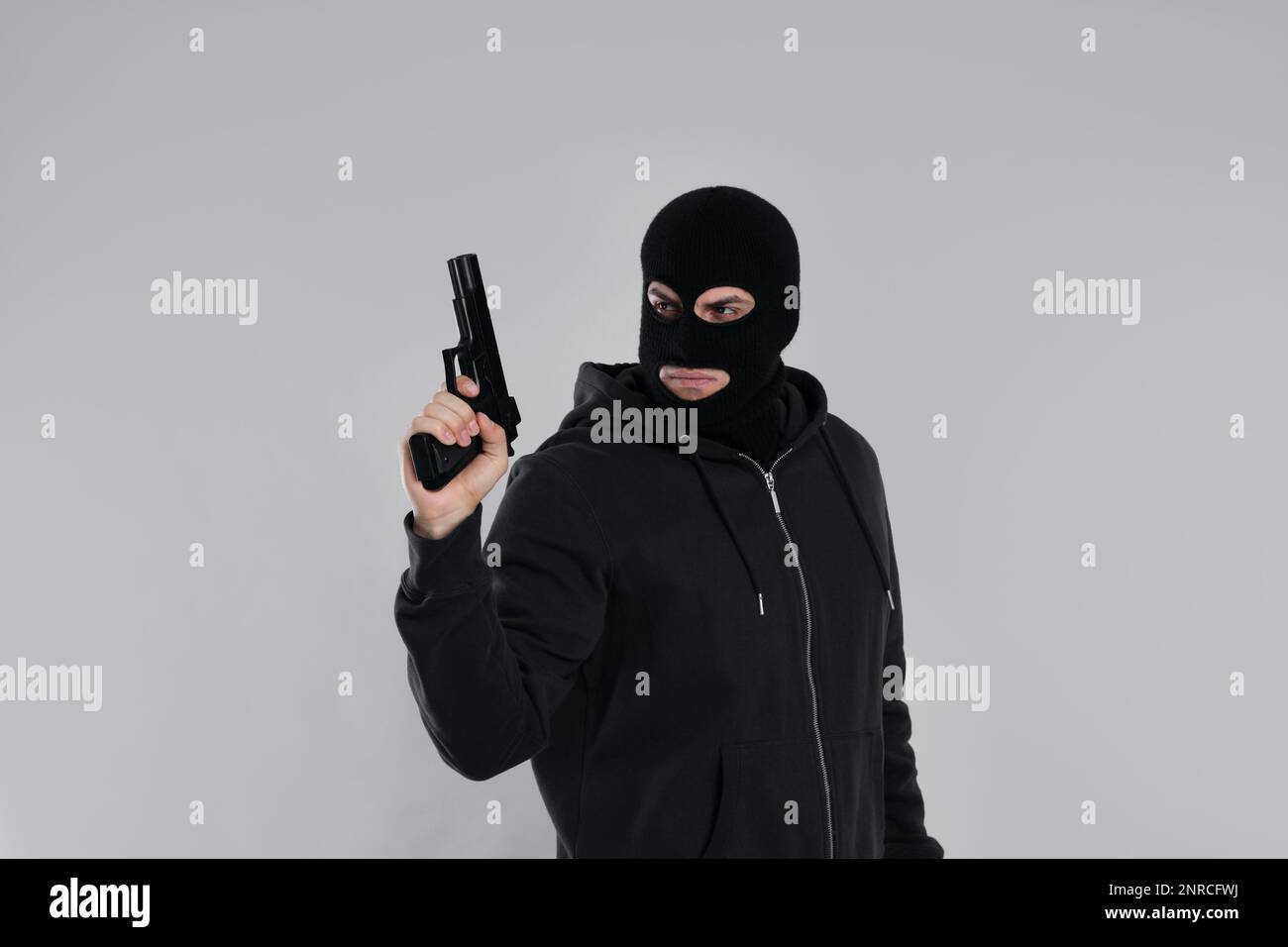 Man wearing black balaclava with gun on light grey background Stock ...