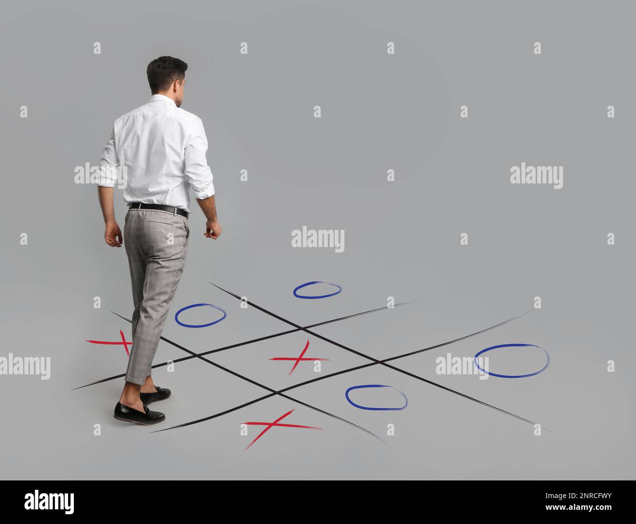 Man and illustration of tic-tac-toe game on grey background, back view ...