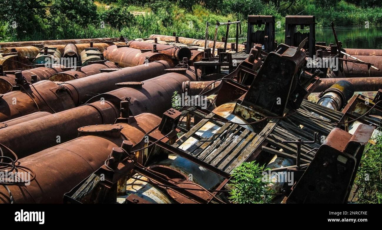 Rusty metal scrapyard on the bank of water reservoir. Remains of metal ...