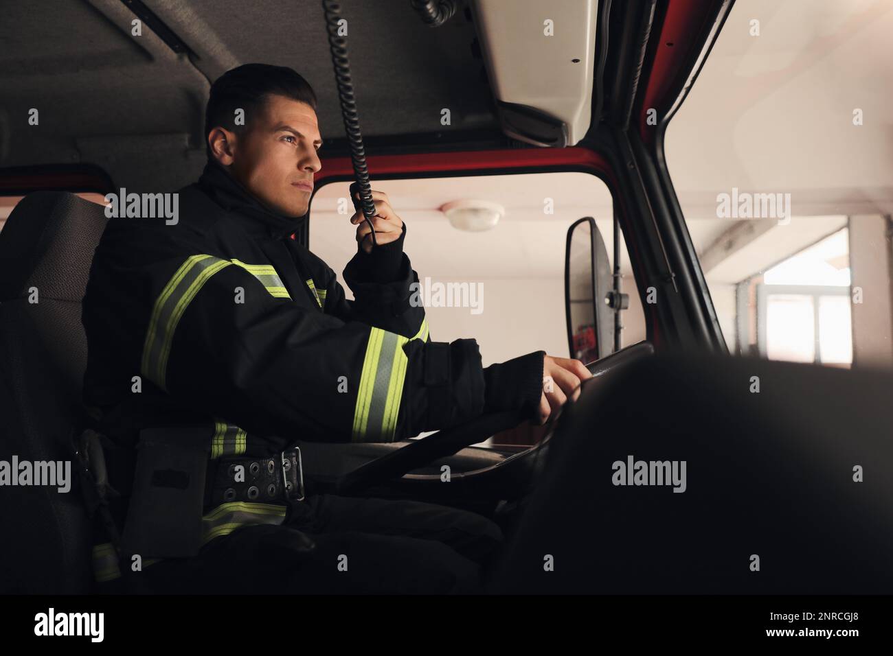 Firefighter using radio set while driving fire truck Stock Photo - Alamy