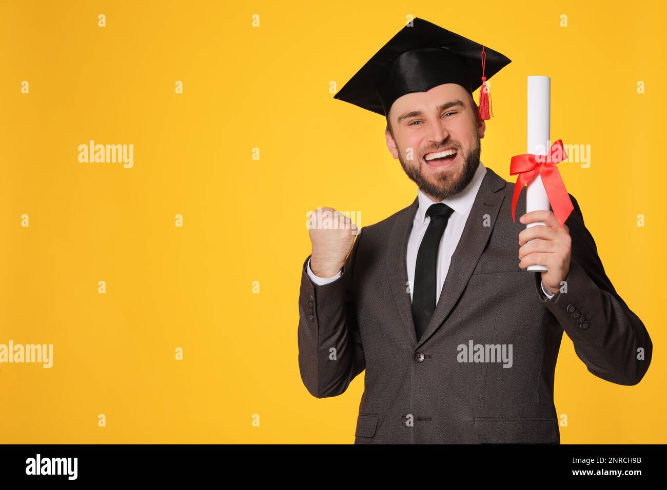 Emotional student with graduation hat and diploma on yellow background ...