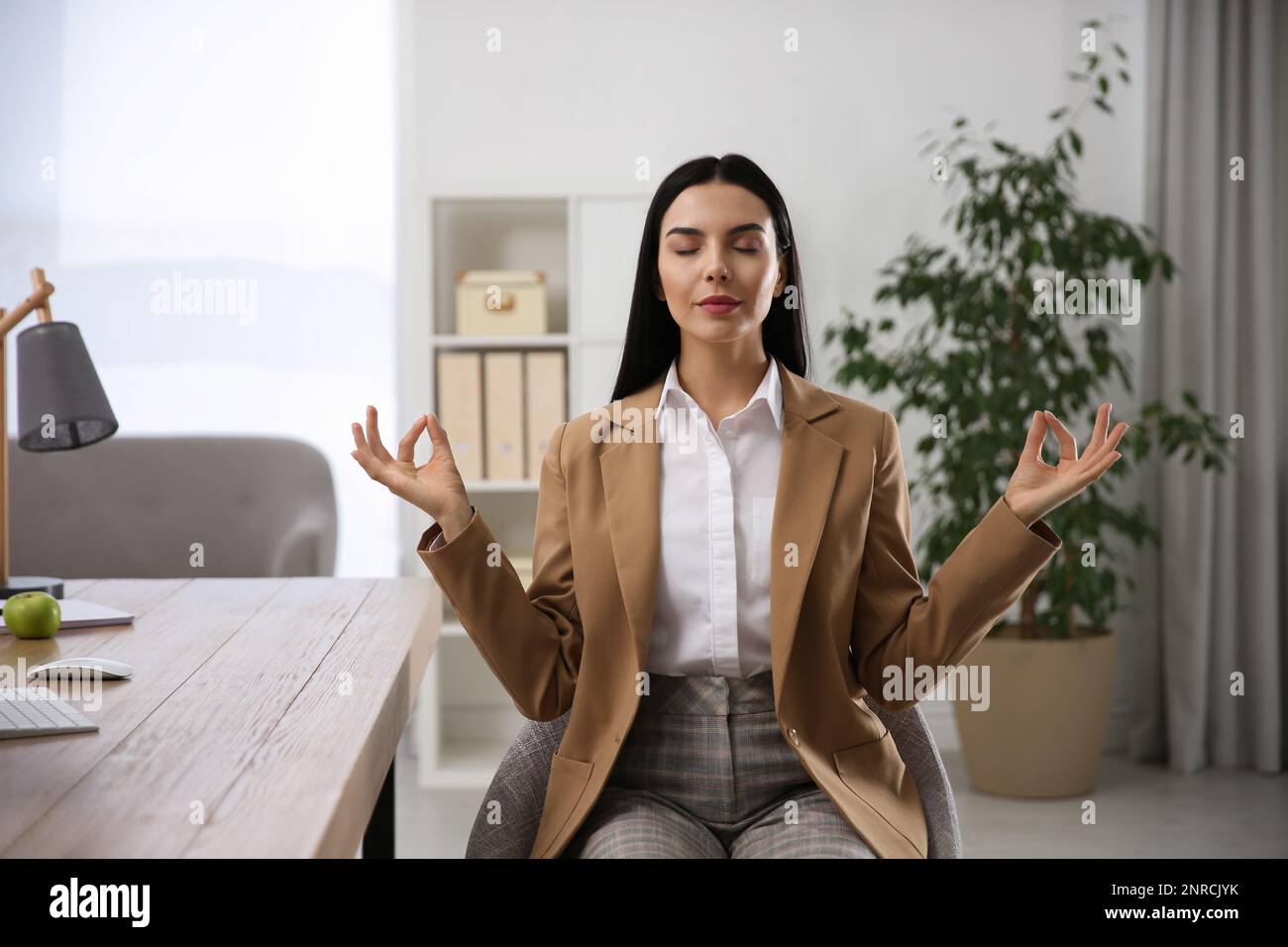 Young woman meditating at workplace. Stress relief exercise Stock Photo ...
