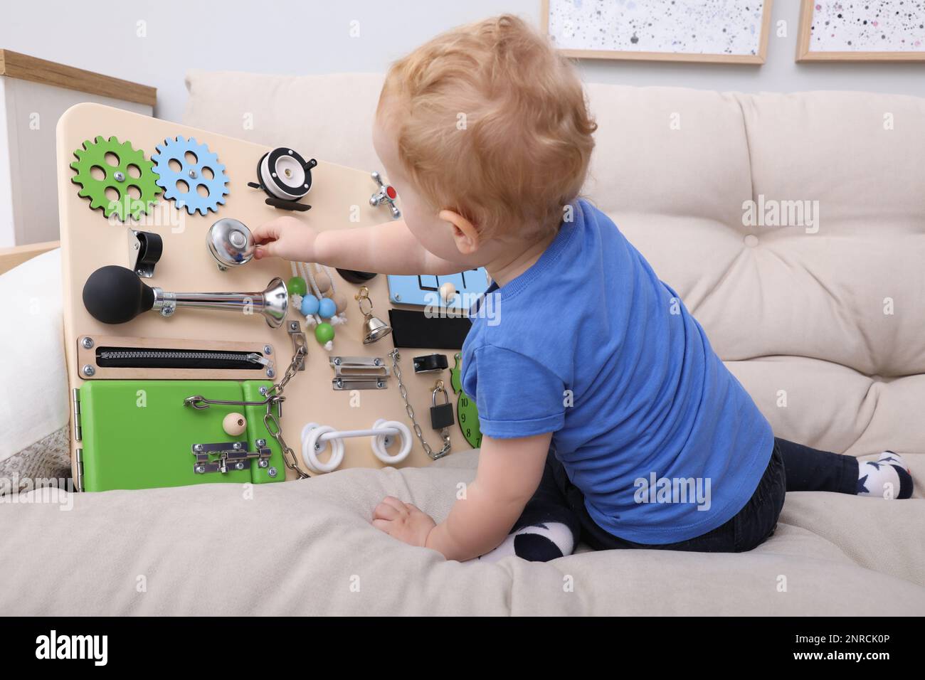 Cute little boy playing with busy board on sofa at home Stock Photo - Alamy