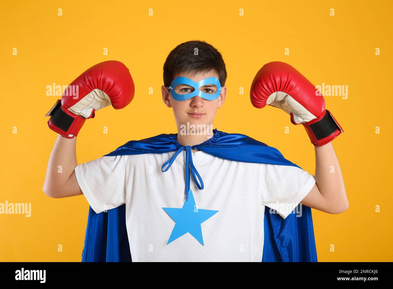 Teenage boy in superhero costume on yellow background Stock Photo - Alamy