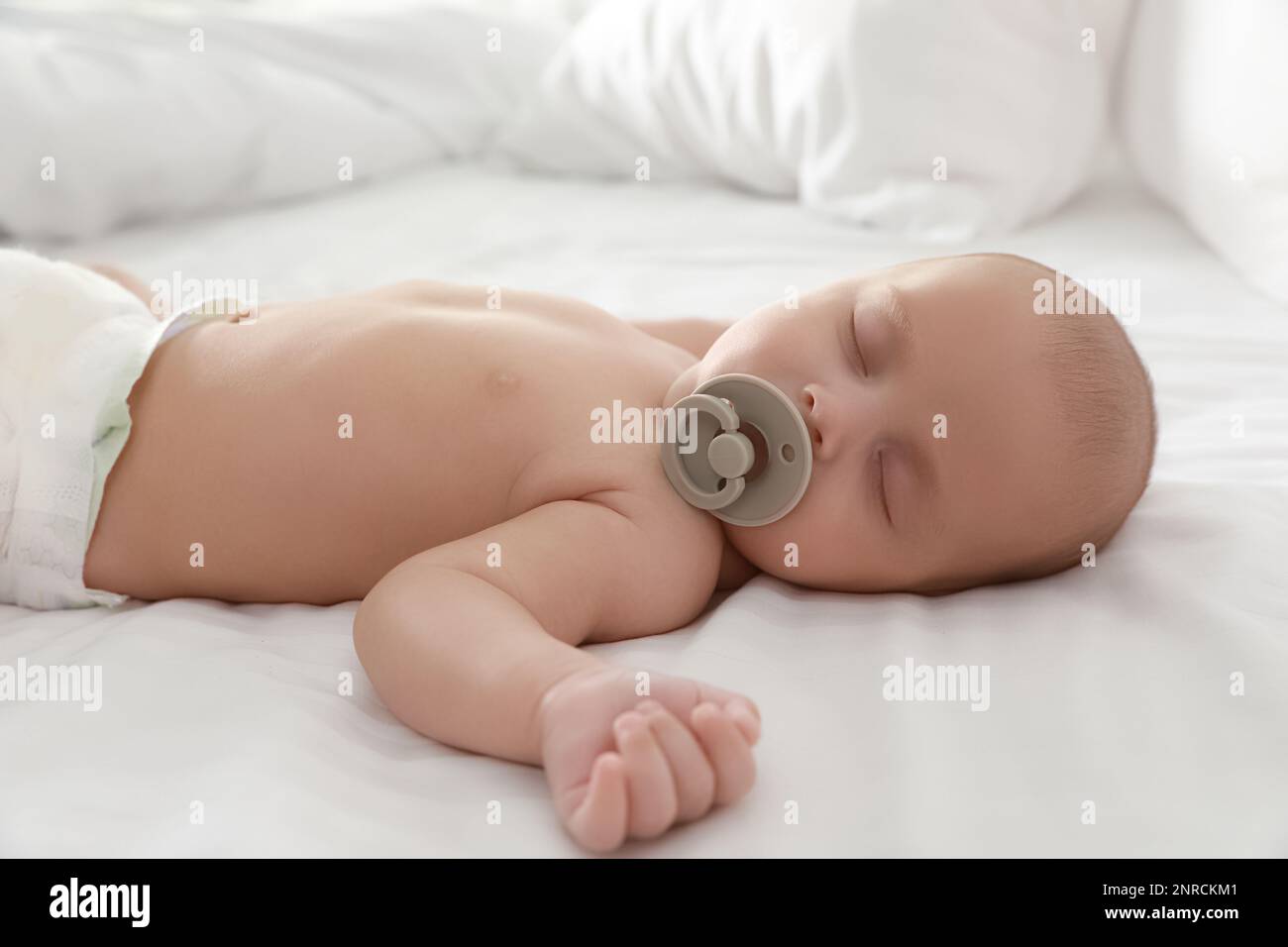 Cute little baby with pacifier sleeping on bed Stock Photo - Alamy