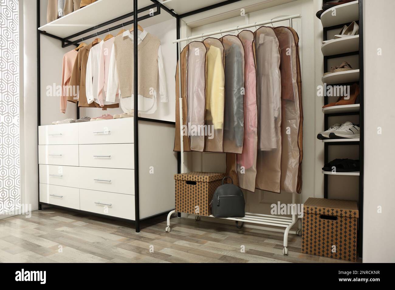 Garment bags with clothes on rack in dressing room Stock Photo - Alamy