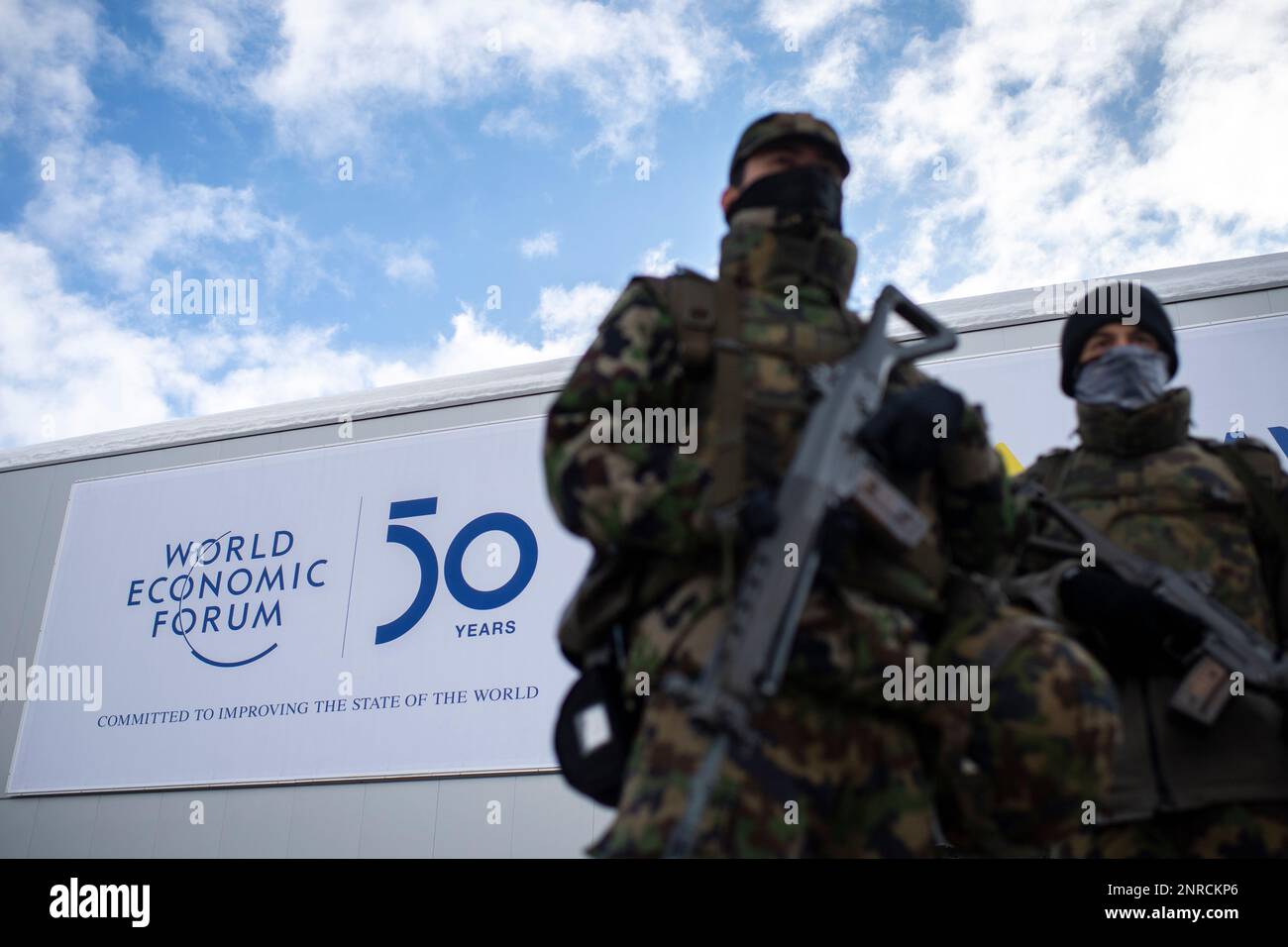 The logo of the WEF is seen behind soldiers of the Swiss Army on guard ...