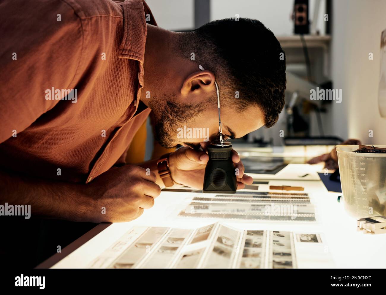 Man, photographer and magnifying glass for film negatives, zoom and ...