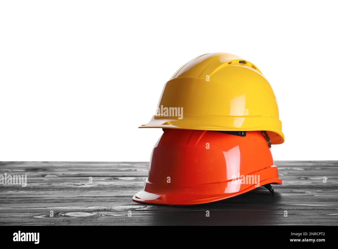 Different hard hats on wooden table against white background. Space for ...