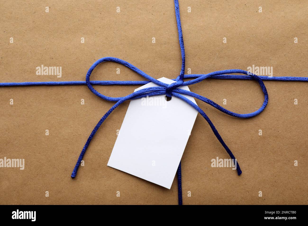 Parcel wrapped in kraft paper with tag as background, closeup Stock ...