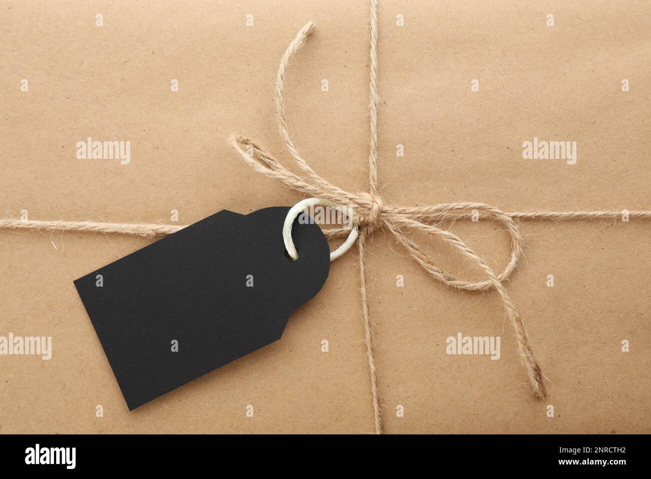 Parcel wrapped in kraft paper with tag as background, closeup Stock ...