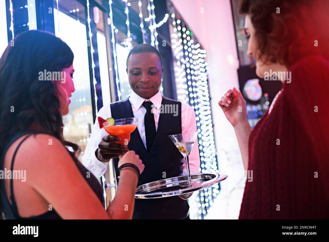 Cocktail for the lady...a waiter serving two women cocktails at a party ...