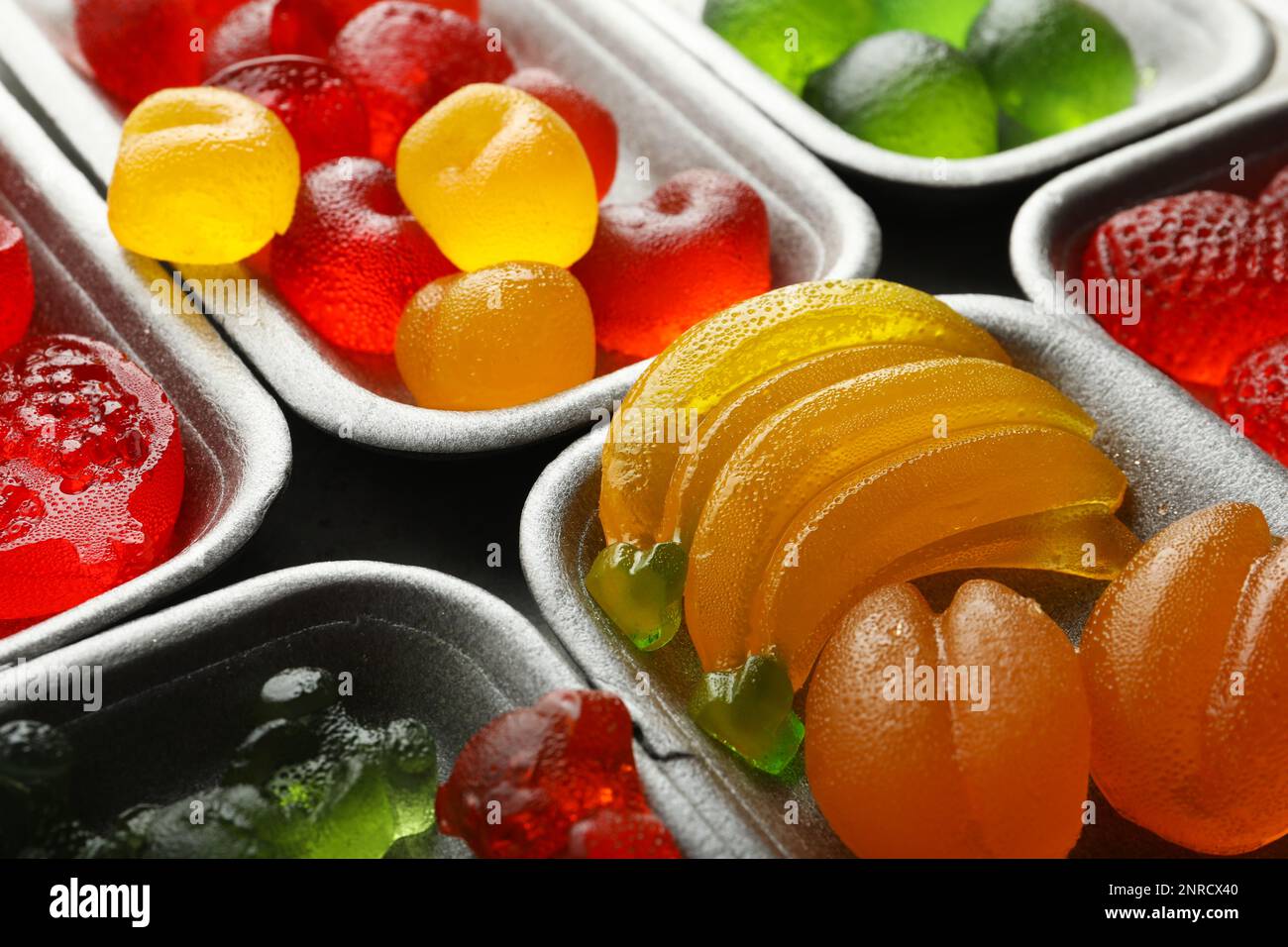 Different delicious gummy candies in containers, closeup Stock Photo ...