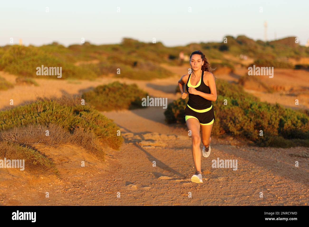 Front vie wof a runner woman running in the mountain towards camera at ...