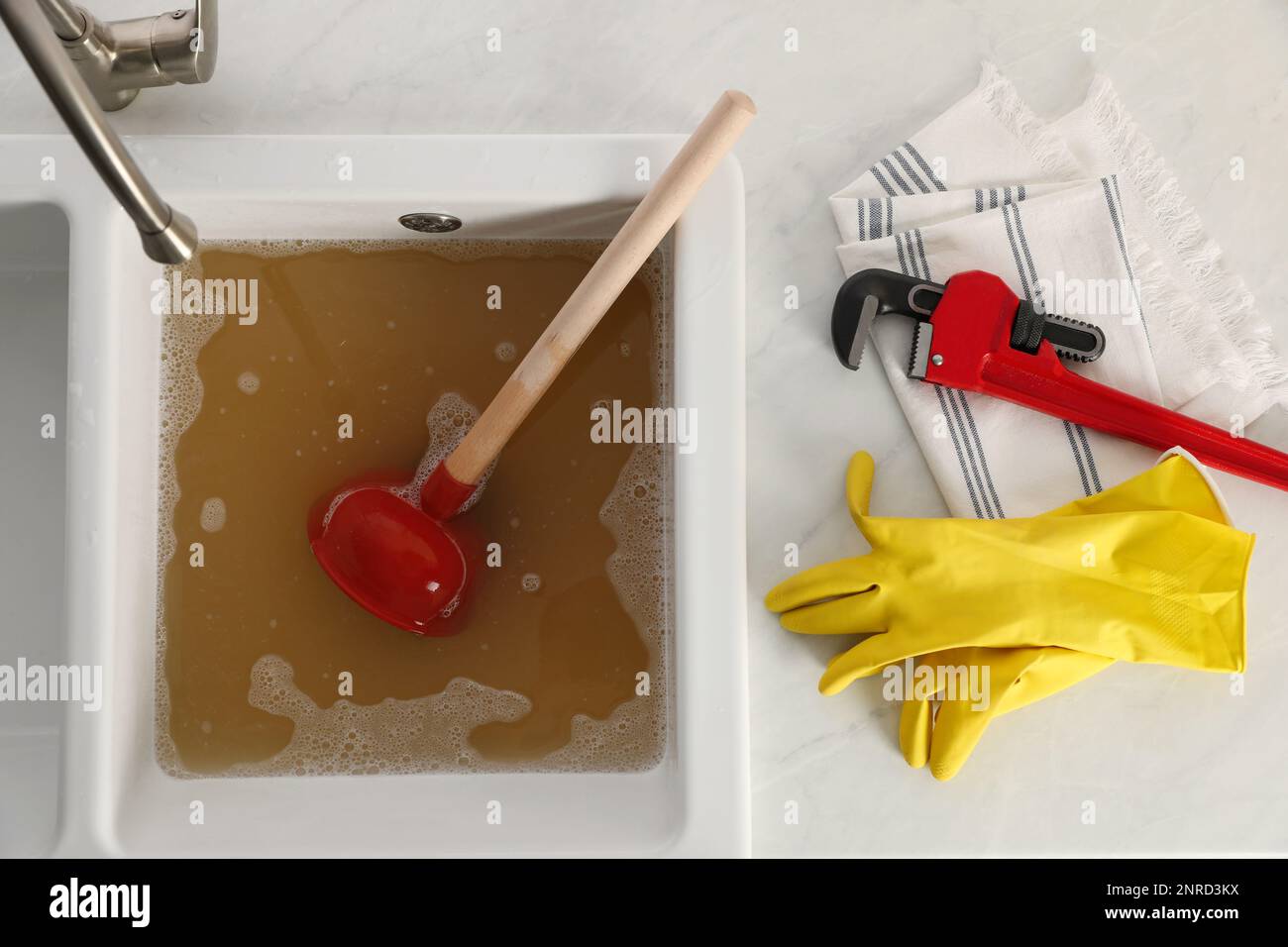 Kitchen counter with clogged sink, plunger and plumber's accessories ...
