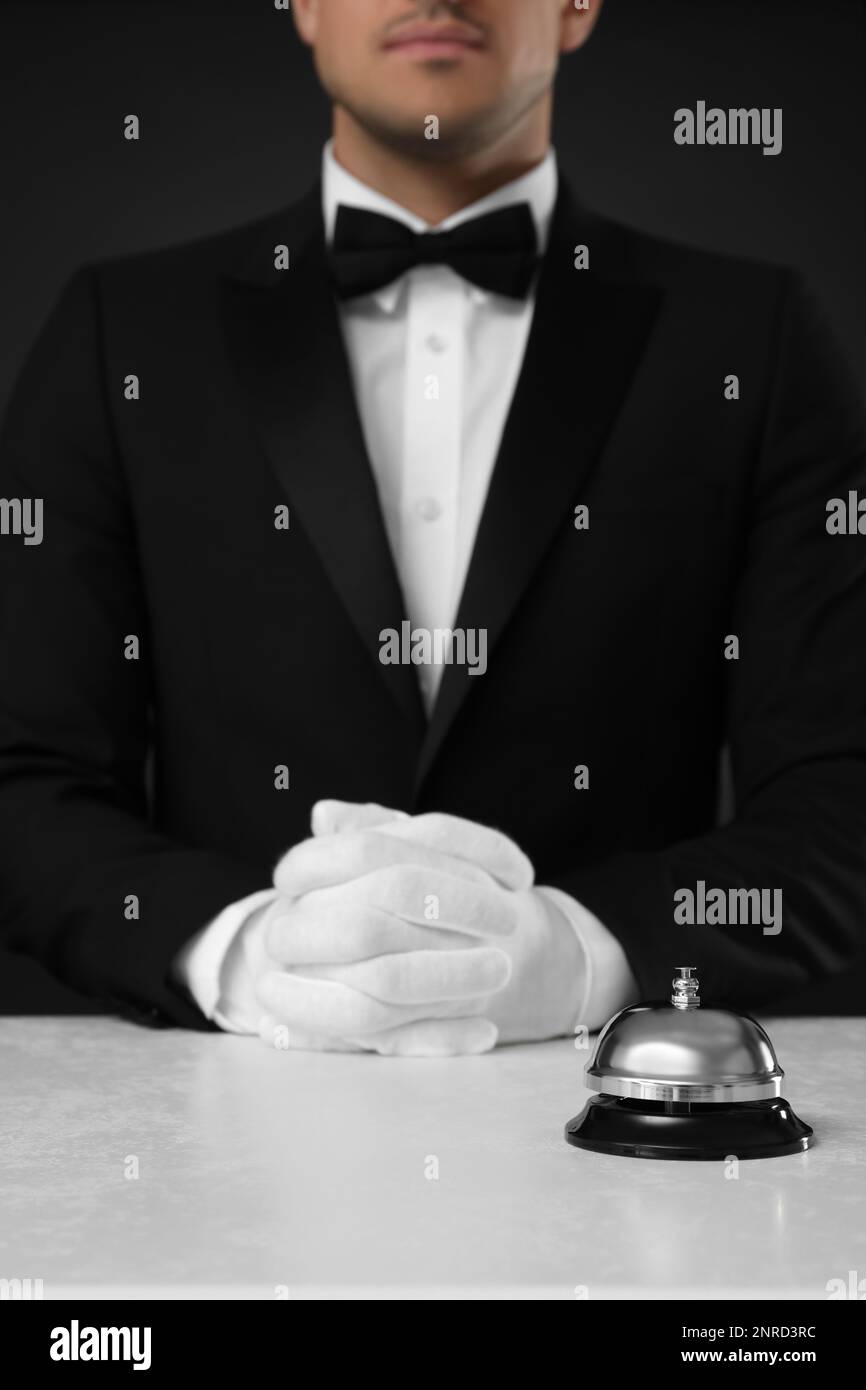 Butler at desk with service bell against black background, closeup view ...