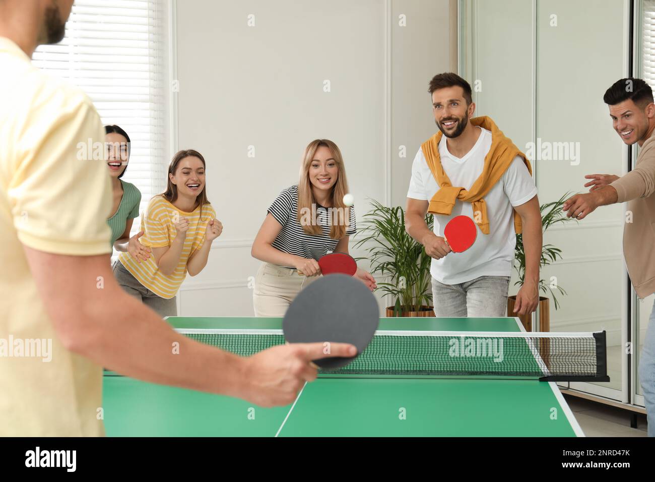 Happy friends playing ping pong together indoors Stock Photo - Alamy
