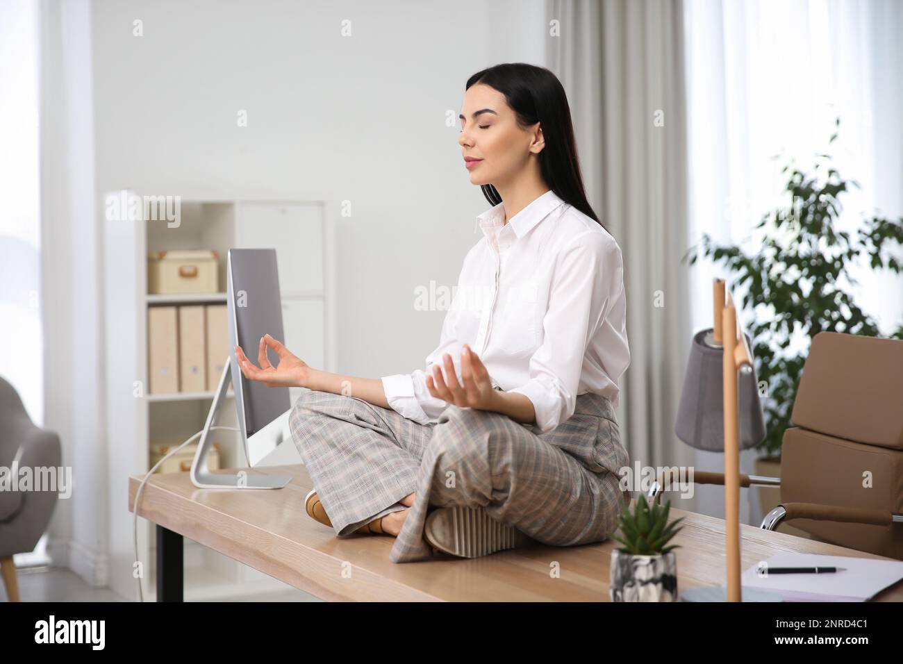 Young woman meditating at workplace. Stress relief exercise Stock Photo ...