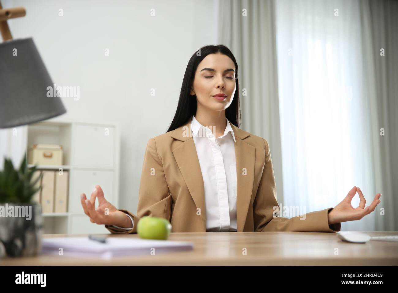 Young woman meditating at workplace. Stress relief exercise Stock Photo ...