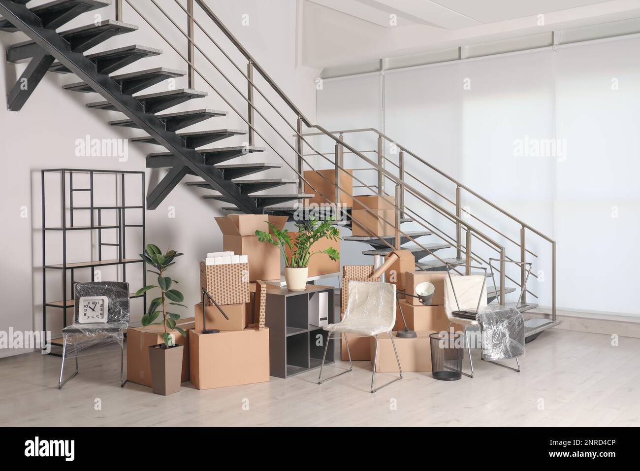 Cardboard boxes with packed stuff near stairs in office. Moving day ...
