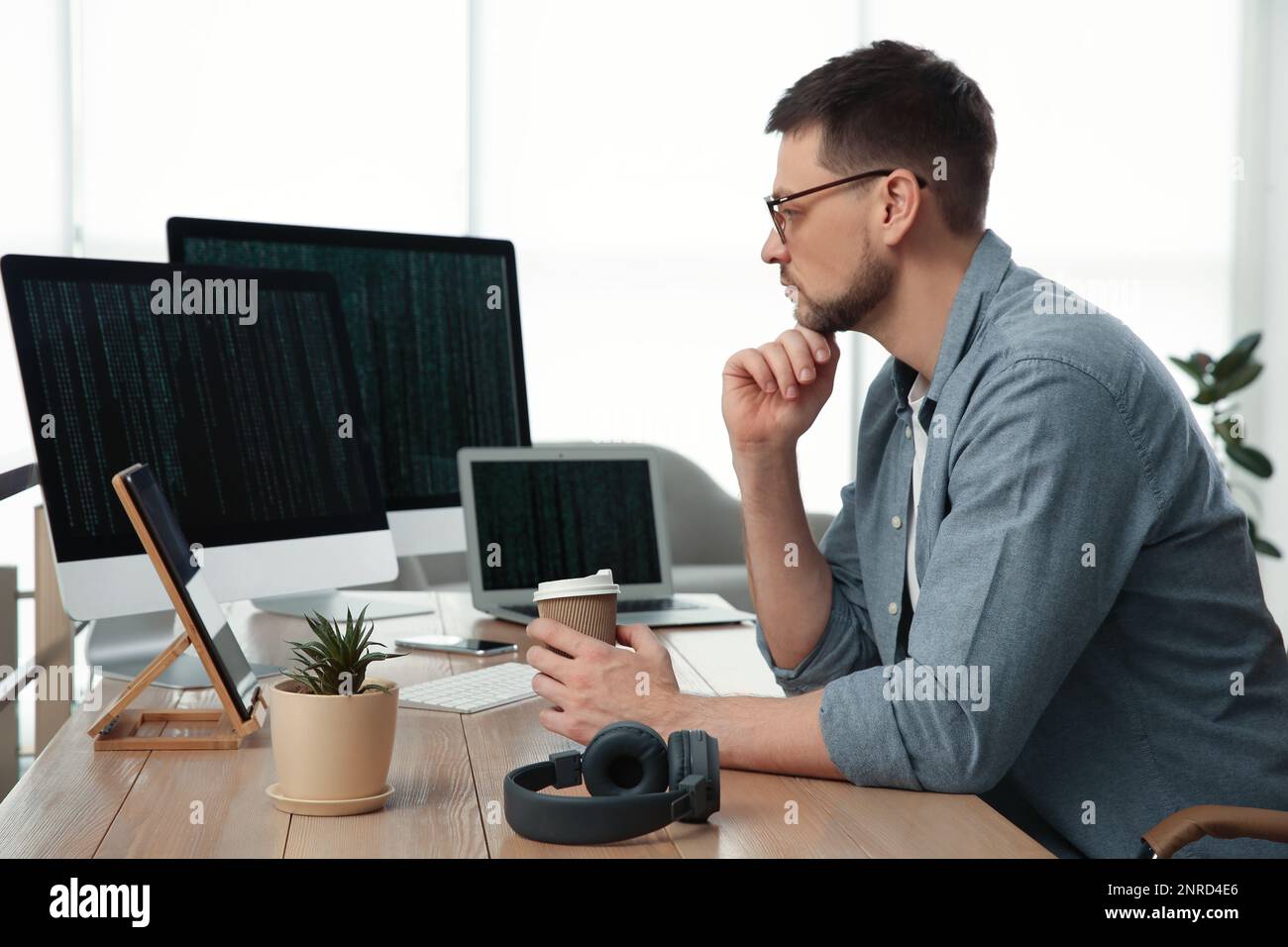 Programmer with coffee working at desk in office Stock Photo - Alamy