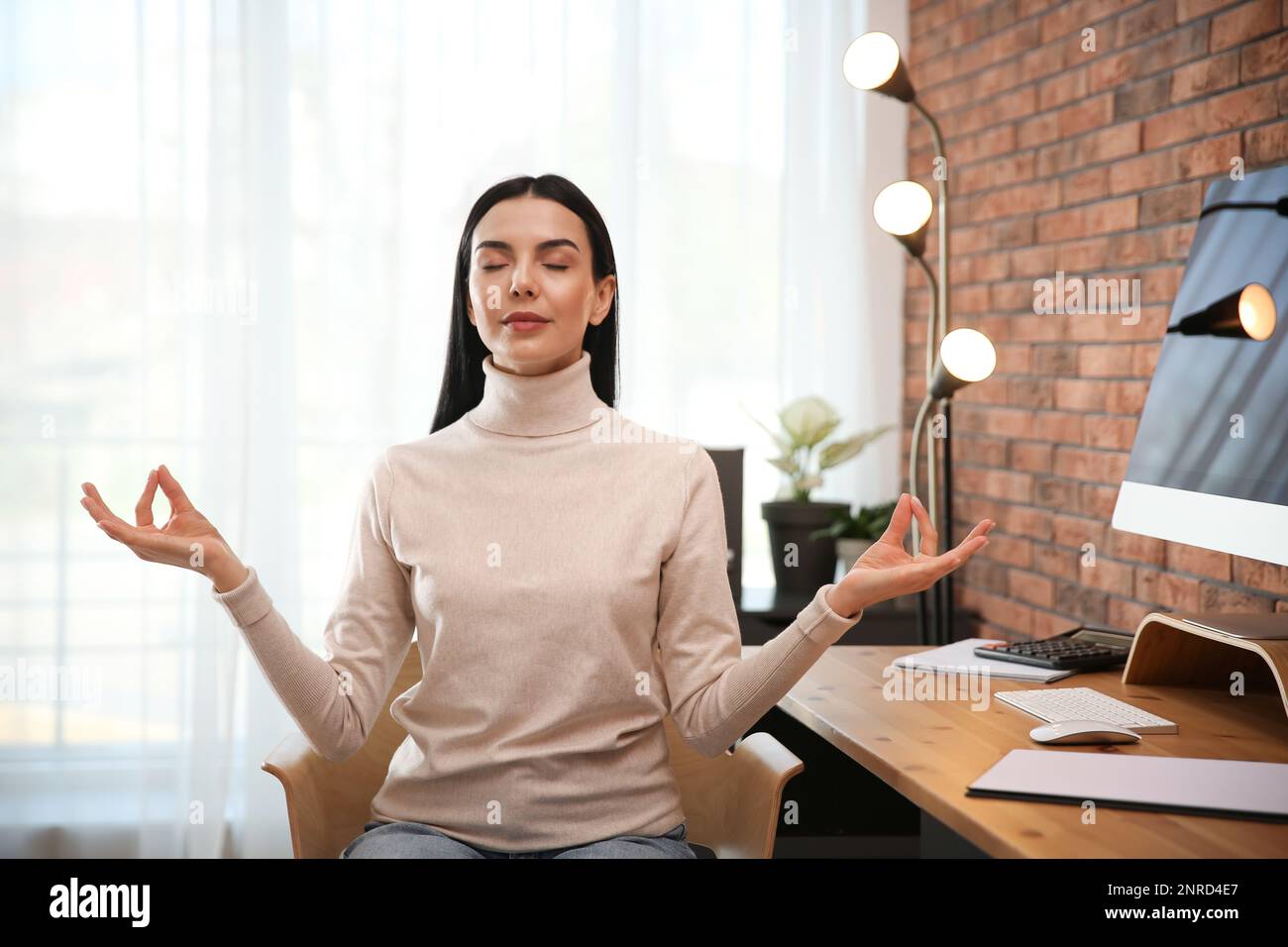 Young woman meditating at workplace. Stress relief exercise Stock Photo ...