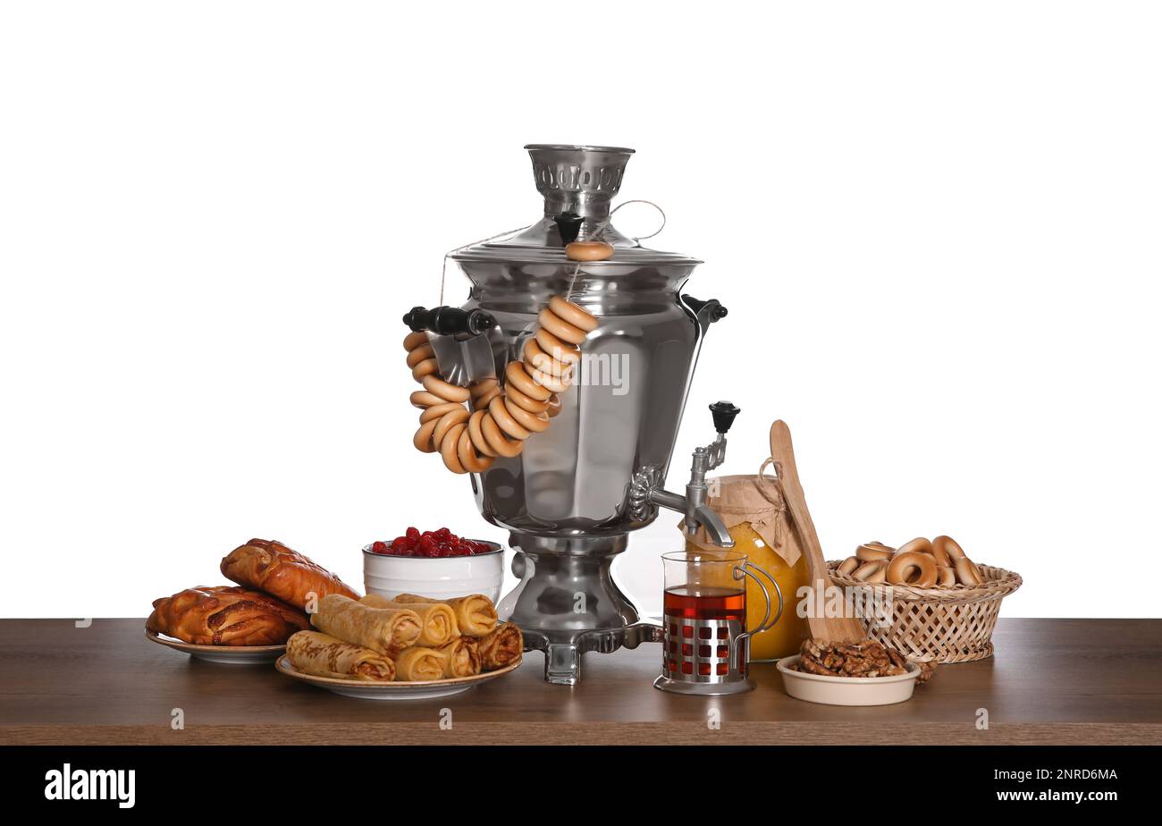 Traditional Russian samovar with treats on wooden table against white ...