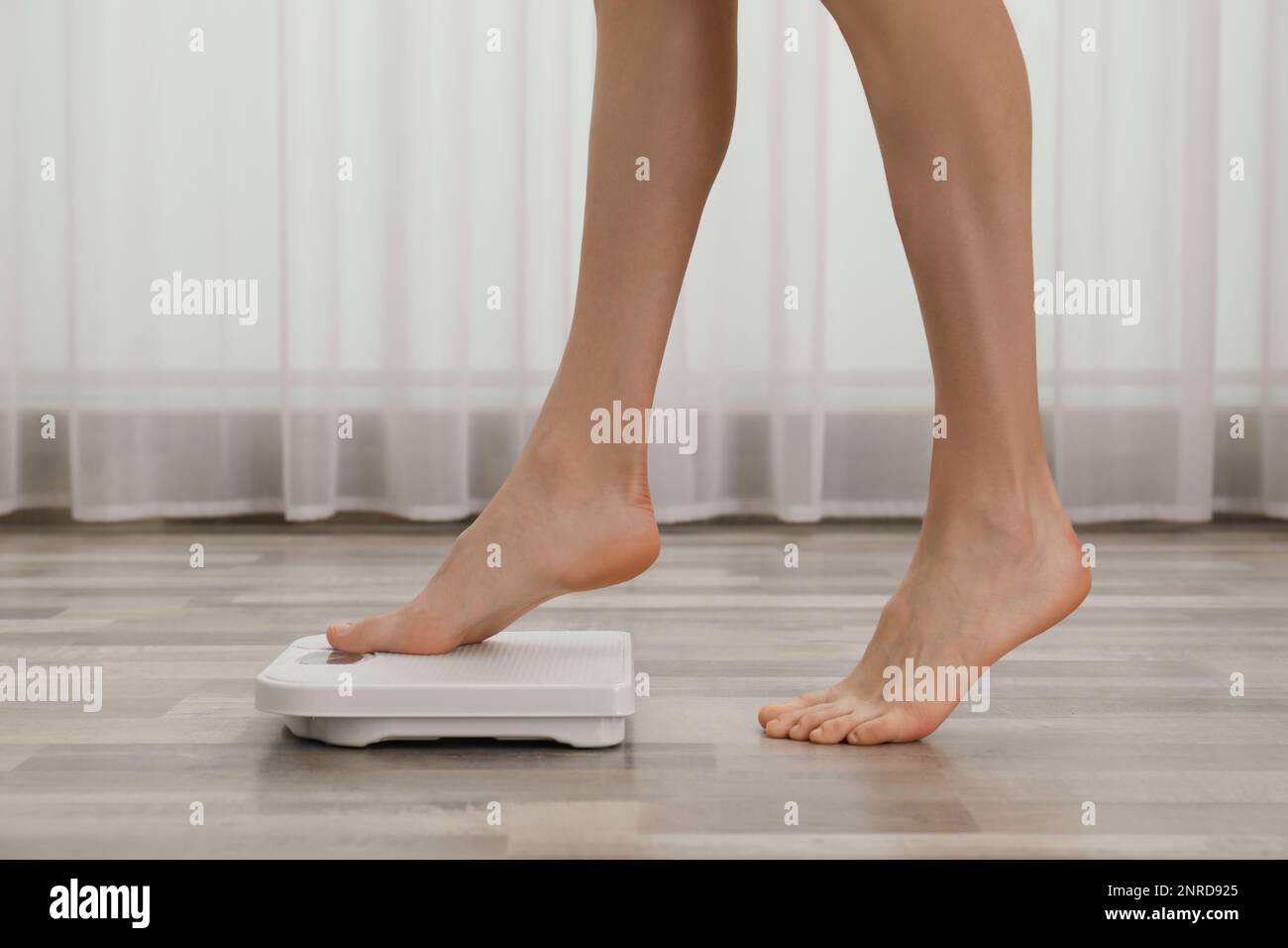 Woman stepping on floor scales indoors, closeup. Weight control Stock ...