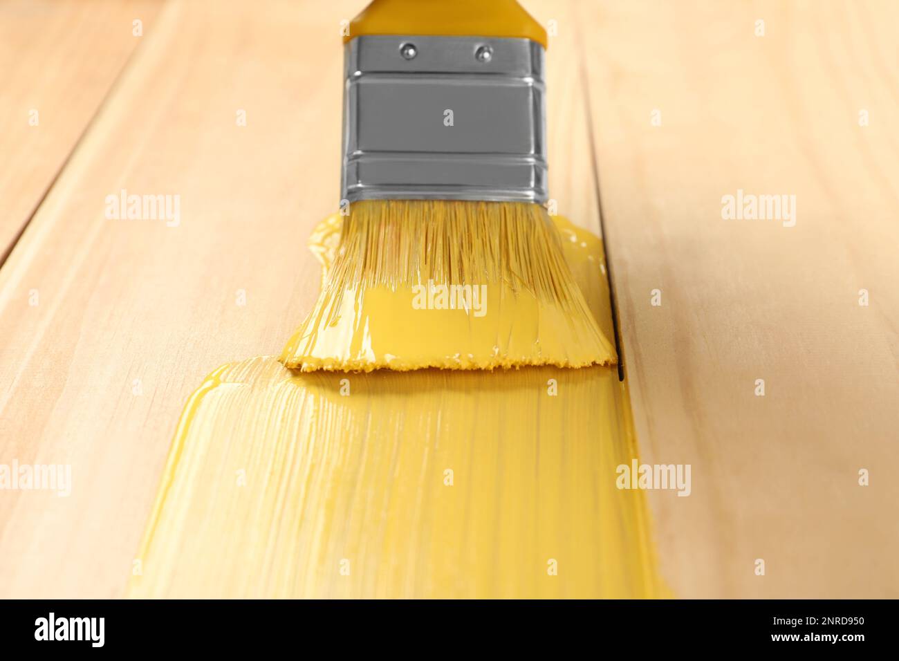 Applying yellow paint onto wooden surface, closeup Stock Photo - Alamy